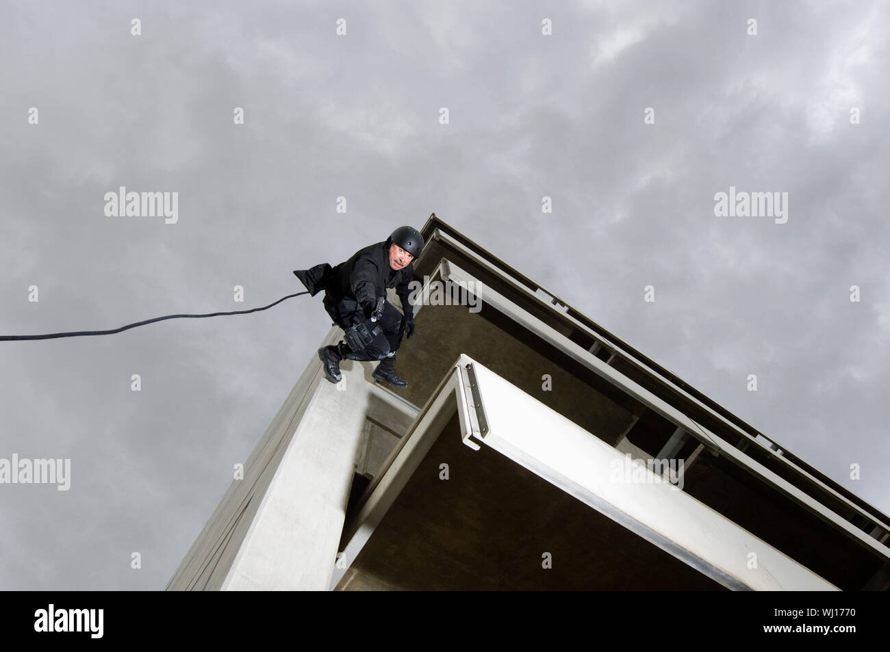Low angle view of a man rappelling down the rope from building against ...