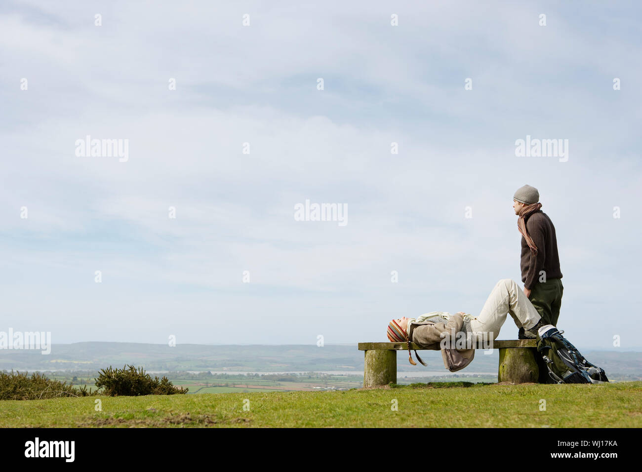 Full length side view of young woman relaxing on park bench with man ...