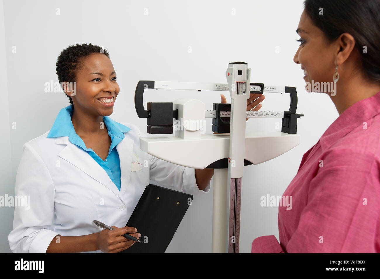 Female doctor weighing patient Stock Photo - Alamy