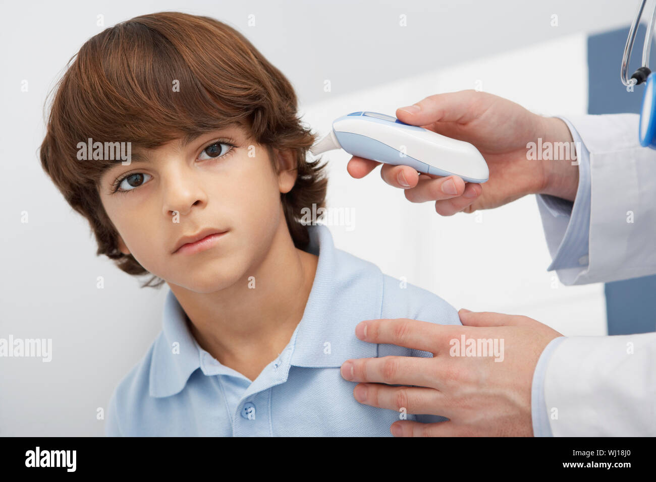 Boy having temperature taken with ear thermometer,portrait Stock Photo ...