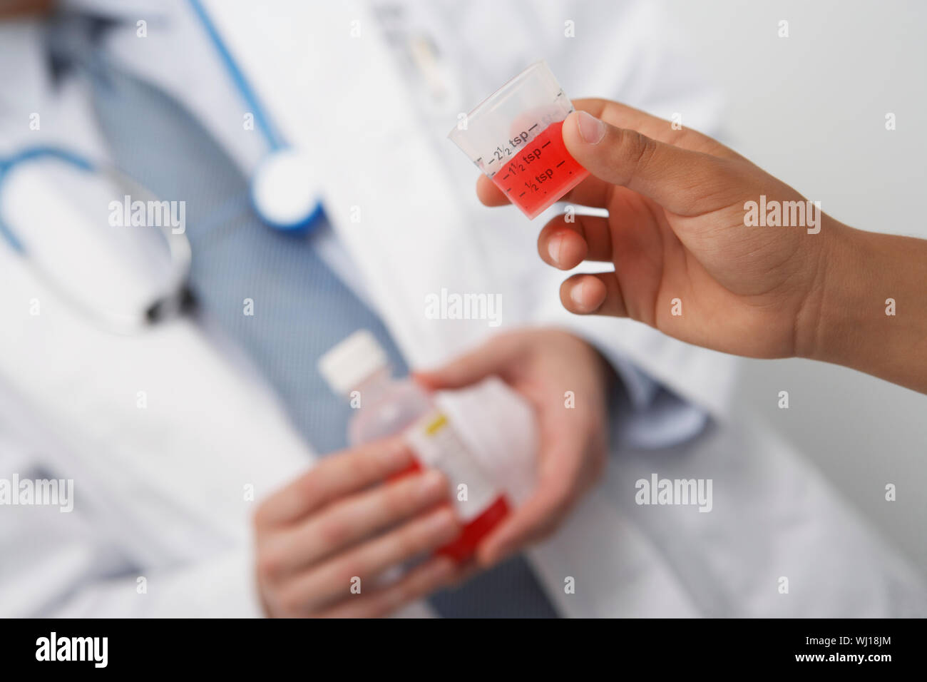 Hand holding medicine in liquid measure Stock Photo - Alamy