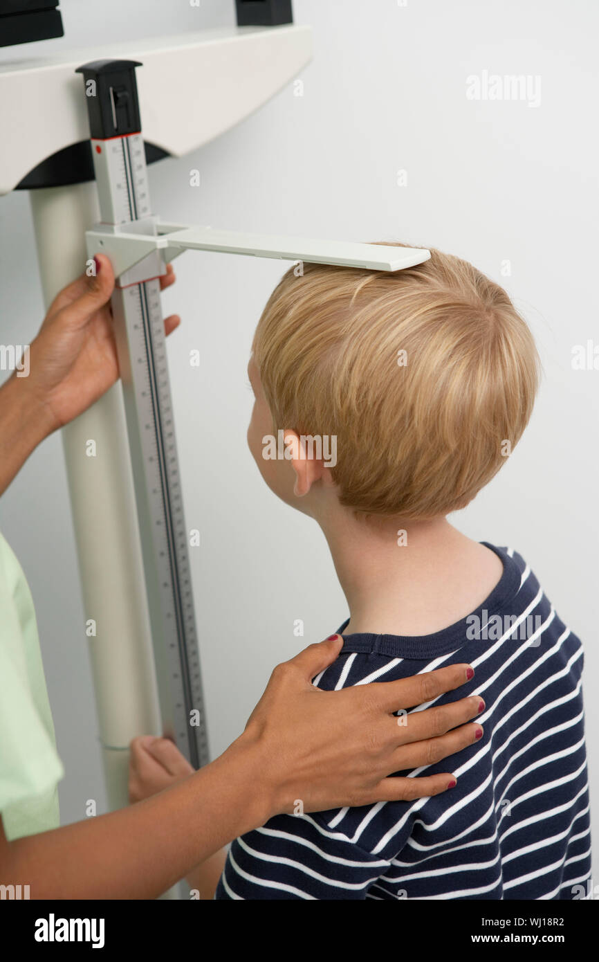Young female nurse measuring boy's height Stock Photo - Alamy