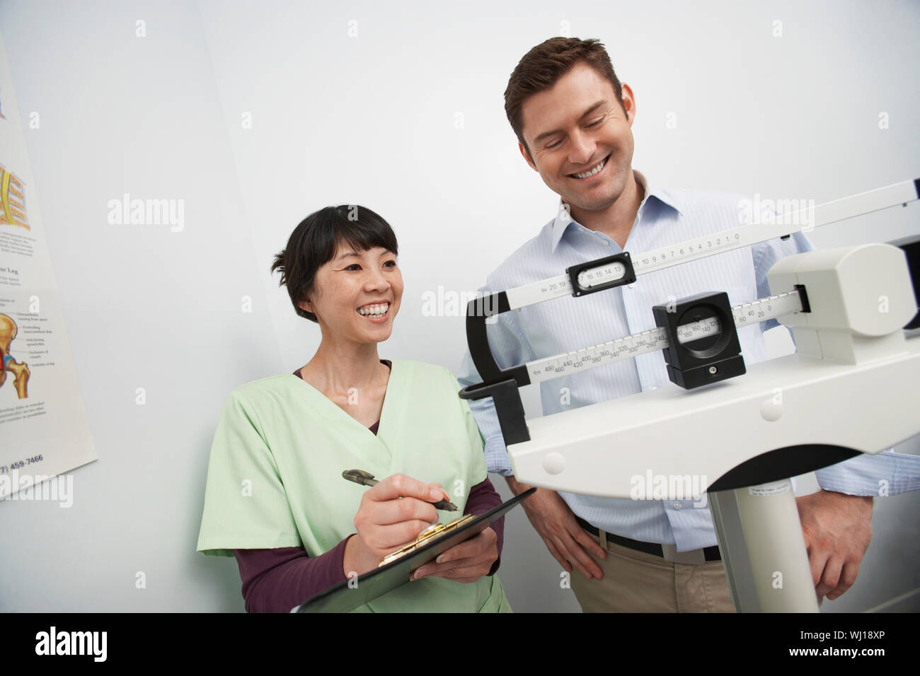 Man standing on weighing scales beside nurse in hospital Stock Photo ...