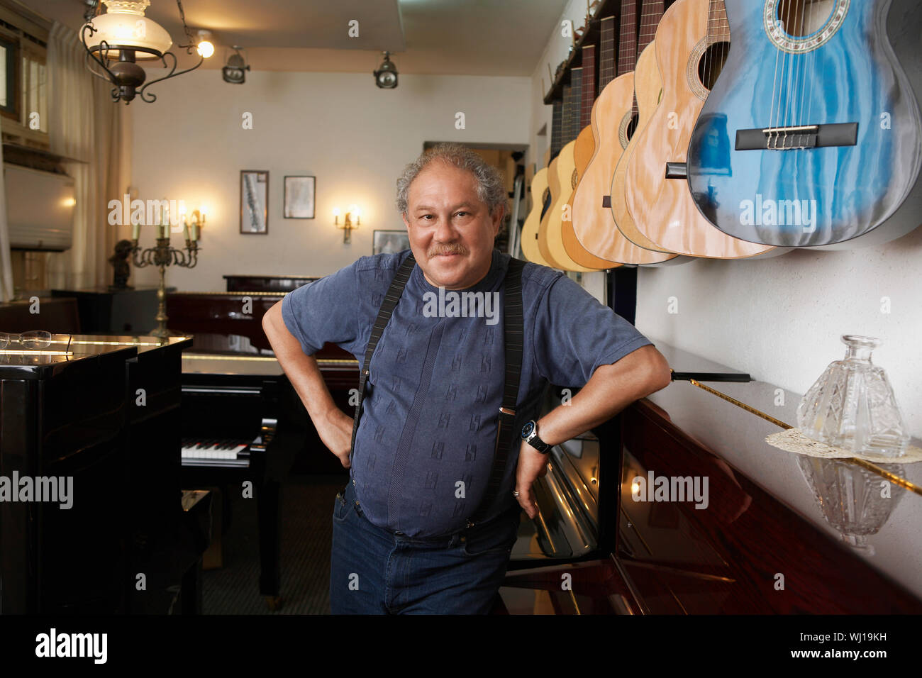 Portrait of middle aged male owner leaning in music store Stock Photo ...