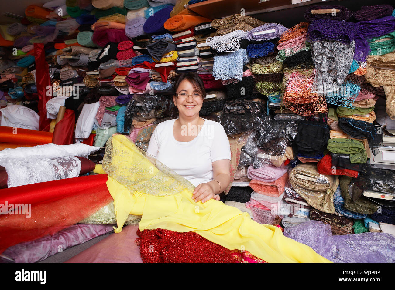 Portrait of confident female fabric store owner standing at counter ...