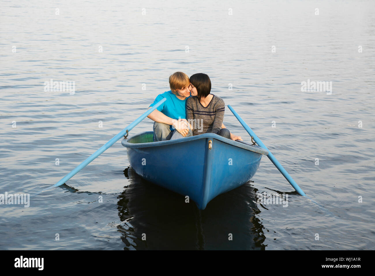 Loving young couple cuddling in rowboat at lake Stock Photo - Alamy