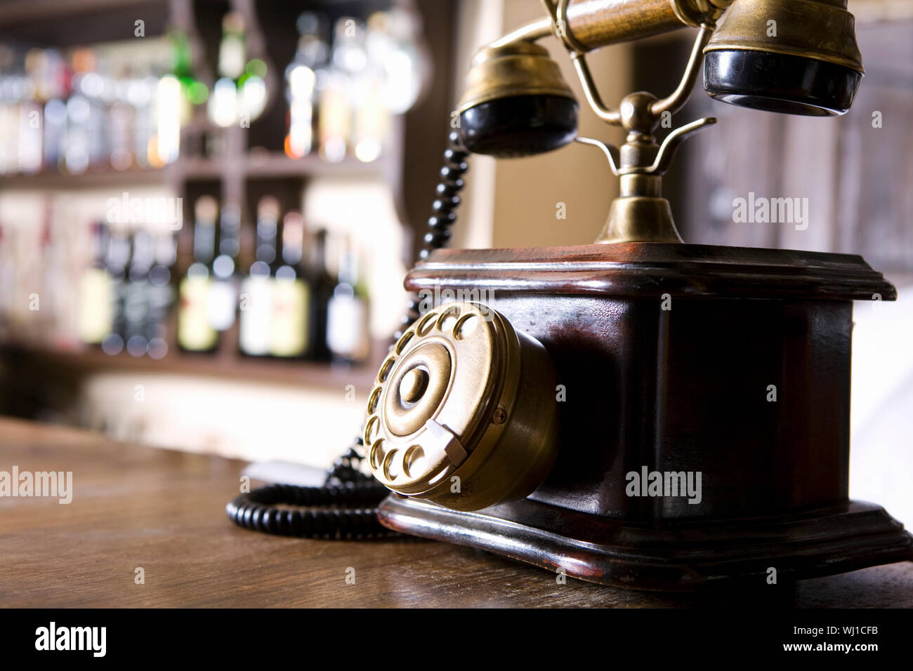 Closeup of a wood and brass antique dial telephone on bar counter Stock ...