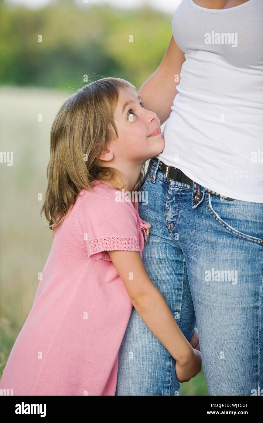 Cute little girl hugging her mother's leg in the field Stock Photo - Alamy