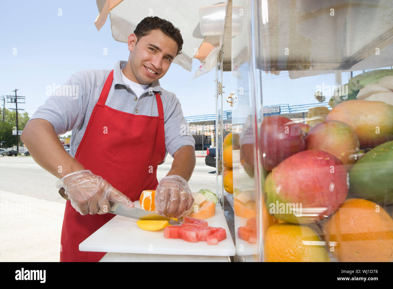 Portrait of male street vendor chopping fruit Stock Photo - Alamy