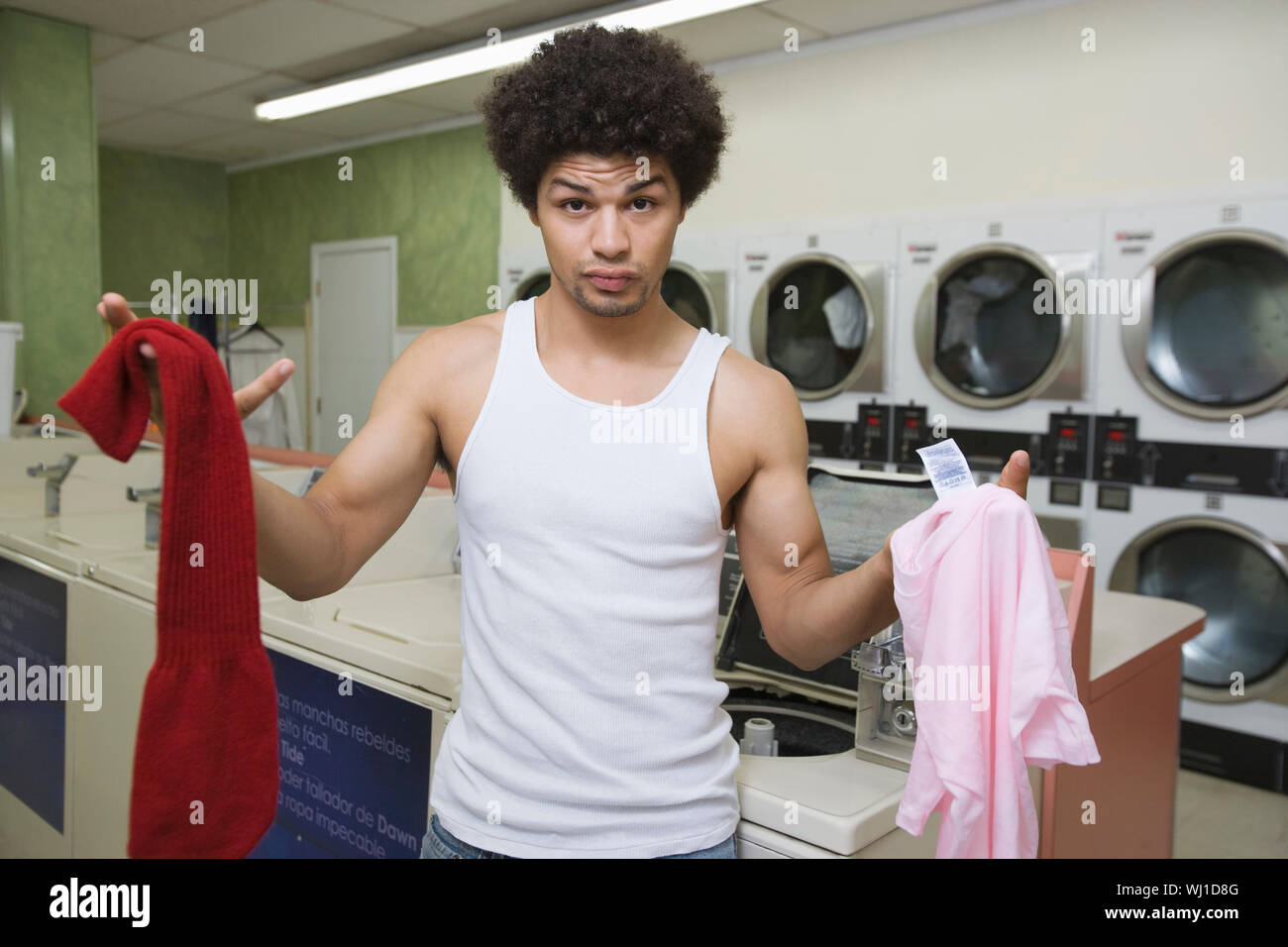 Young man washing clothes at launderette Stock Photo - Alamy