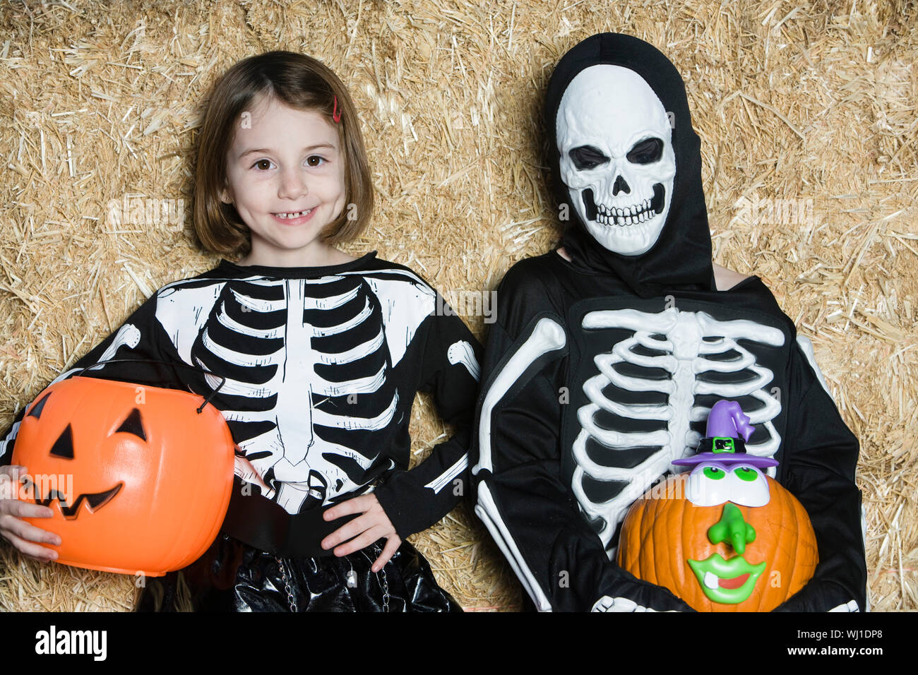 Two multiethnic friends standing in skeleton outfit by the stack of ...