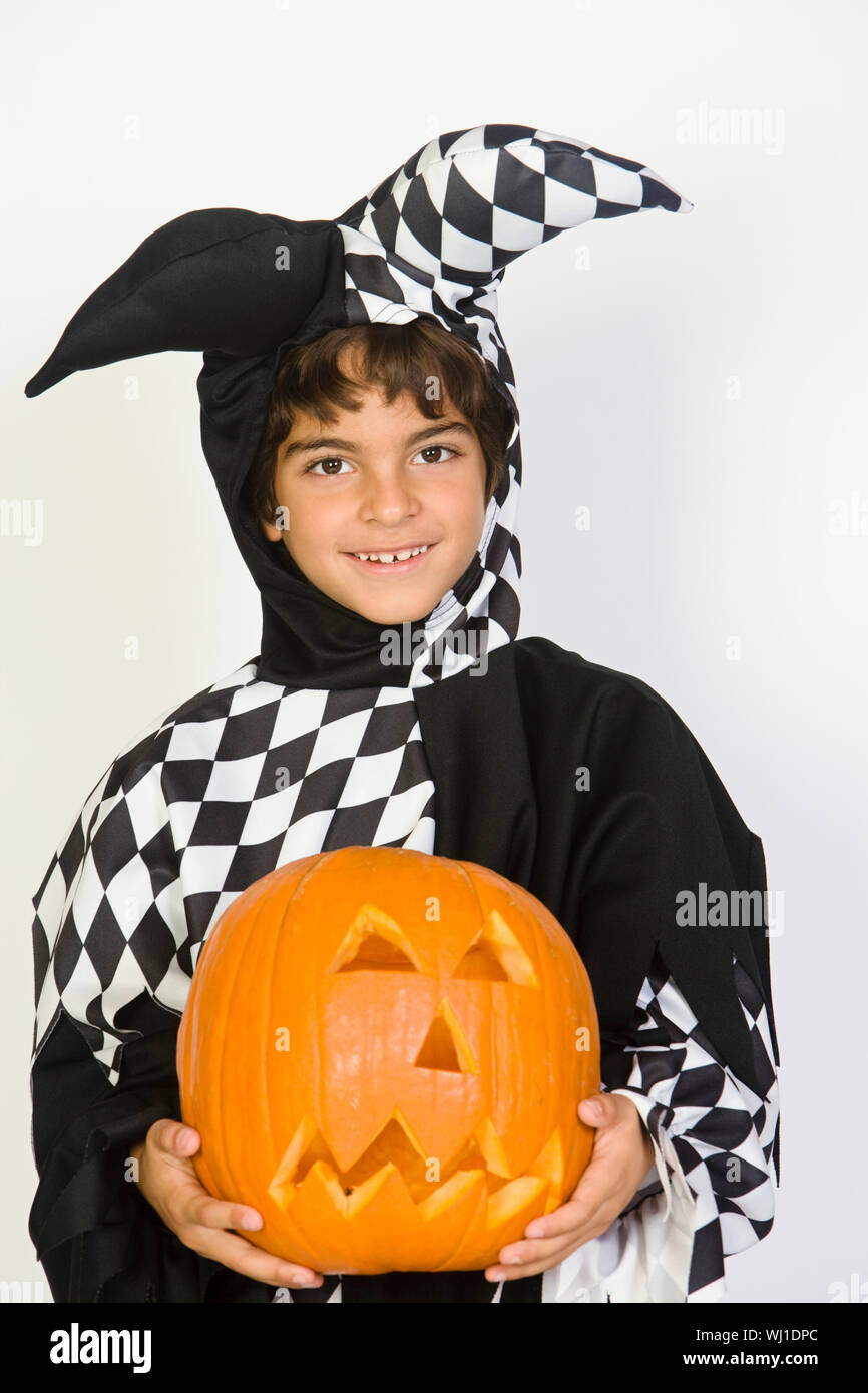 Portrait of a cute little boy in jester outfit with pumpkin isolated ...