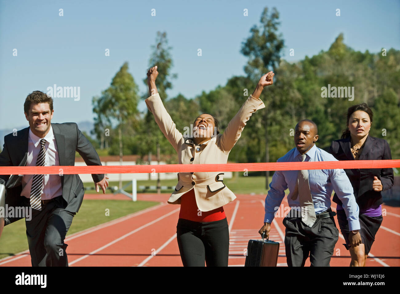 Female businesswoman cheering with competitors running on the racing ...