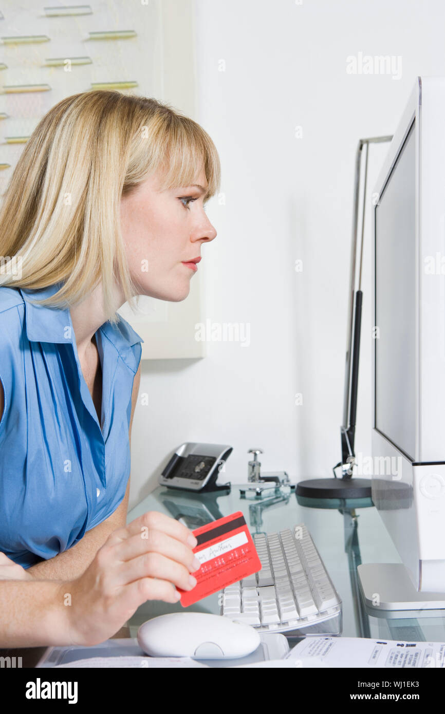 Pretty businesswoman looking intently on computer screen while holding ...