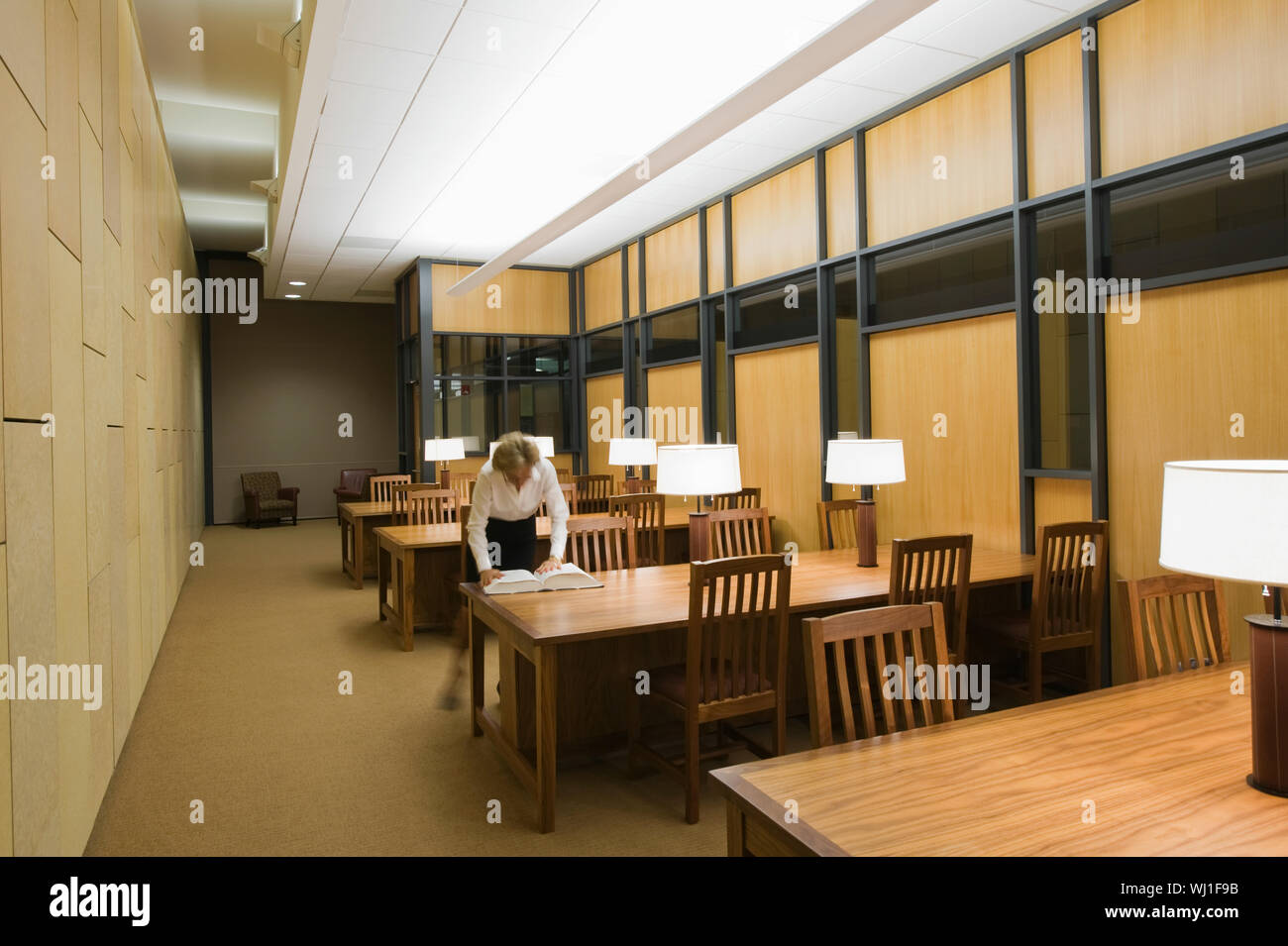 Woman reading book in an empty reading room at library Stock Photo - Alamy