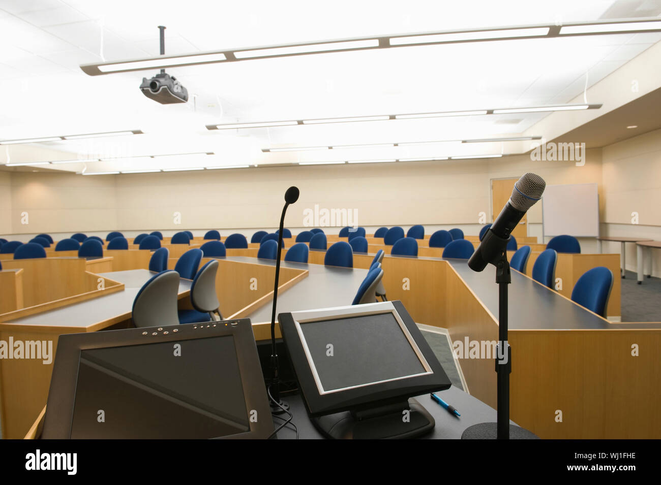 Closeup of microphone and podium with empty chairs in lecture room ...
