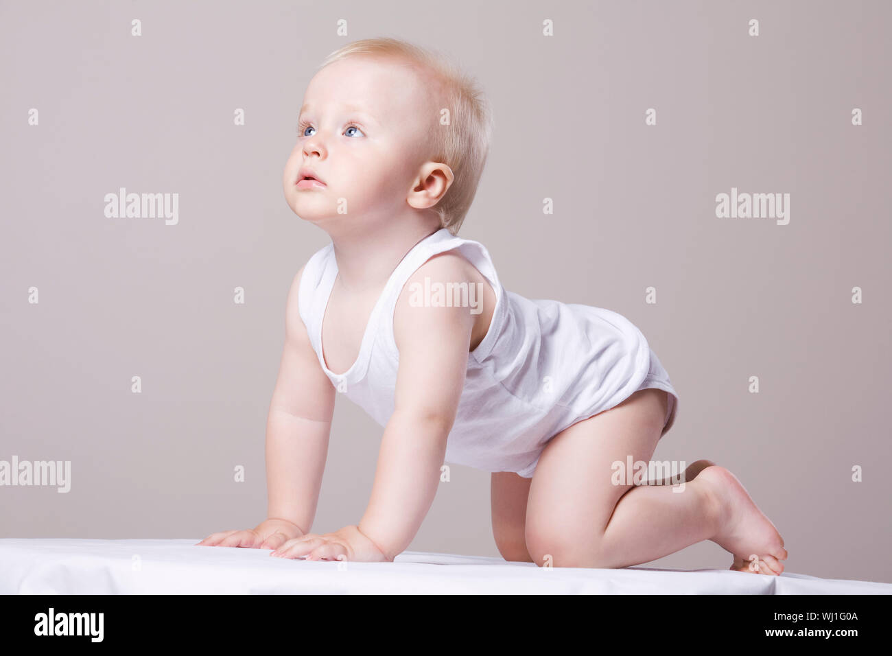 Full length side view of a baby boy crawling as he looks up against ...