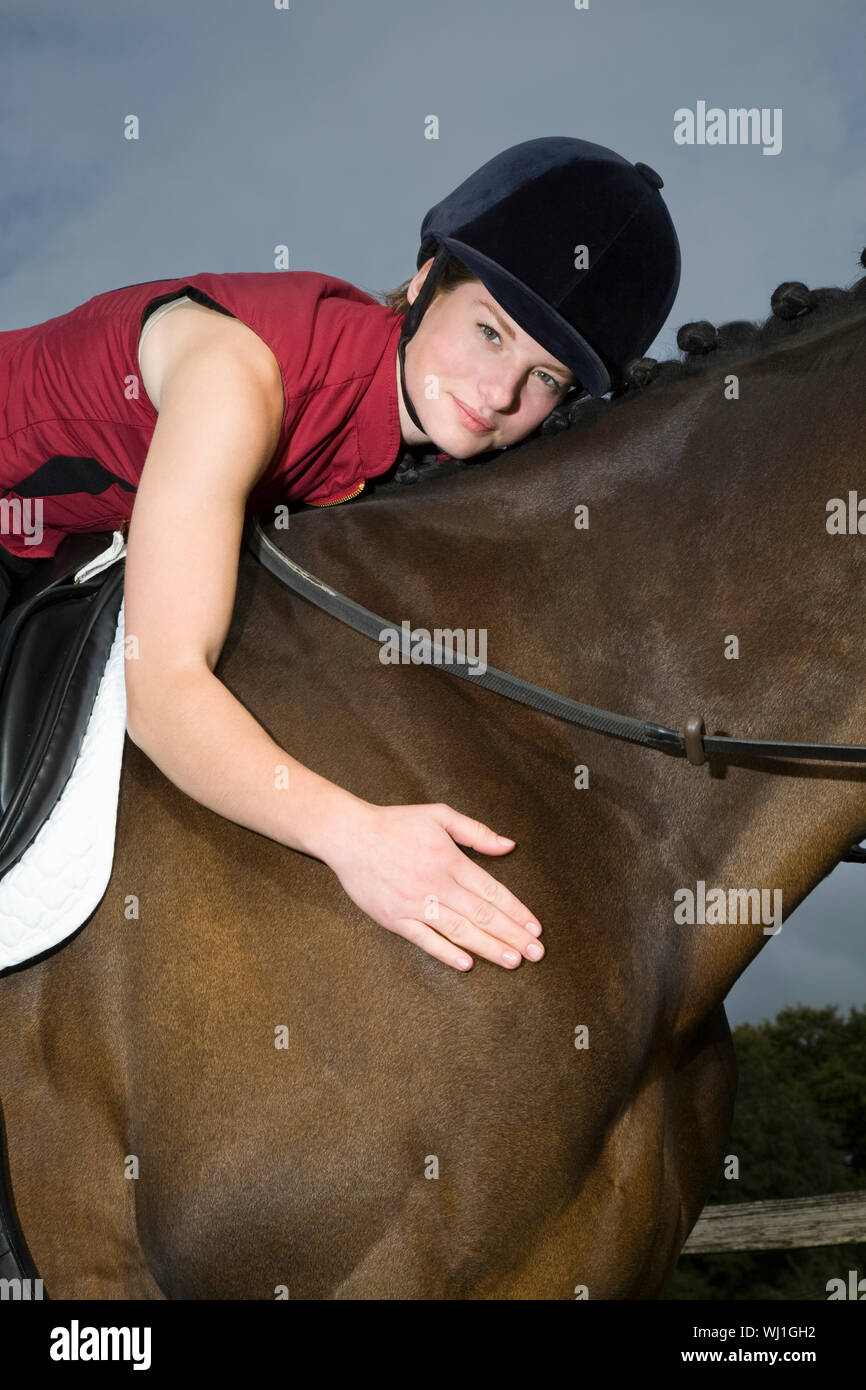 Portrait of a female horseback rider hugging a cropped brown horse ...