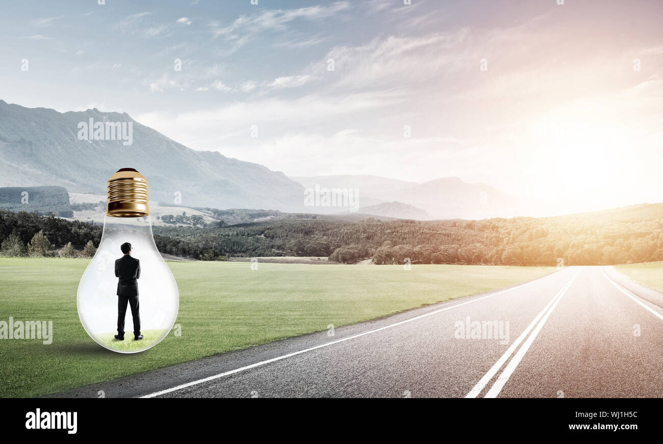 Young businessman trapped inside of light bulb on asphalt road Stock ...