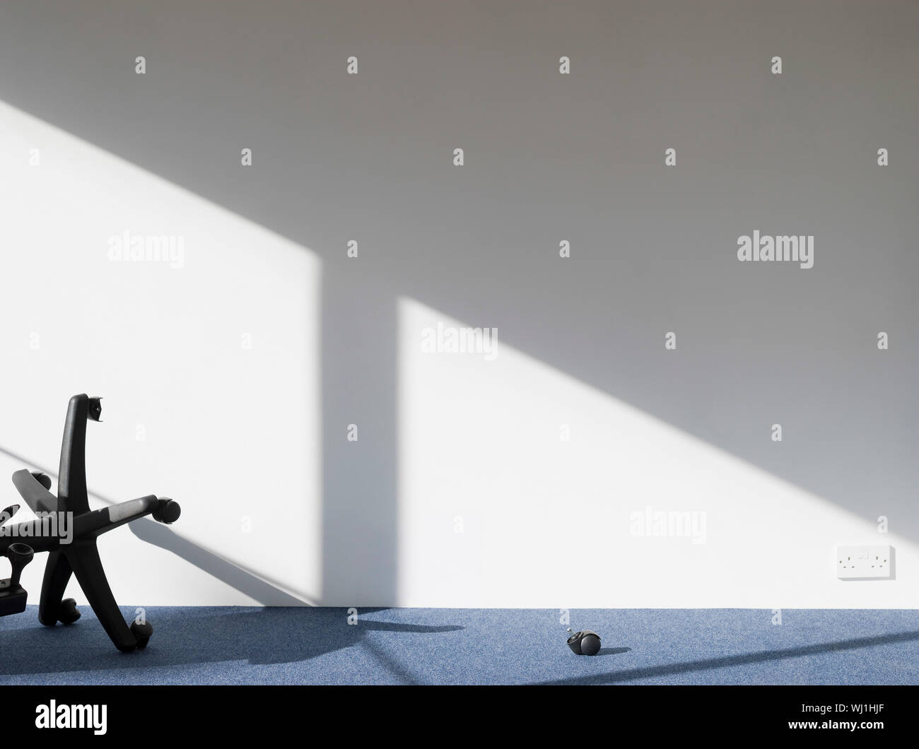 View of a broken office chair casting shadow on wall Stock Photo - Alamy