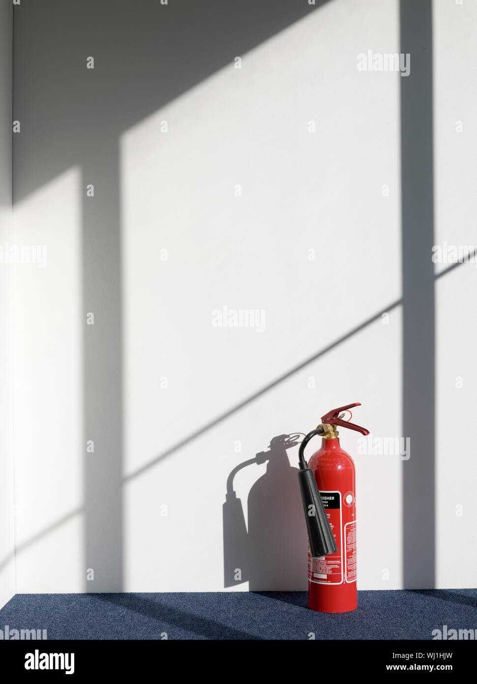 View of a fire extinguisher casting shadow on wall Stock Photo - Alamy