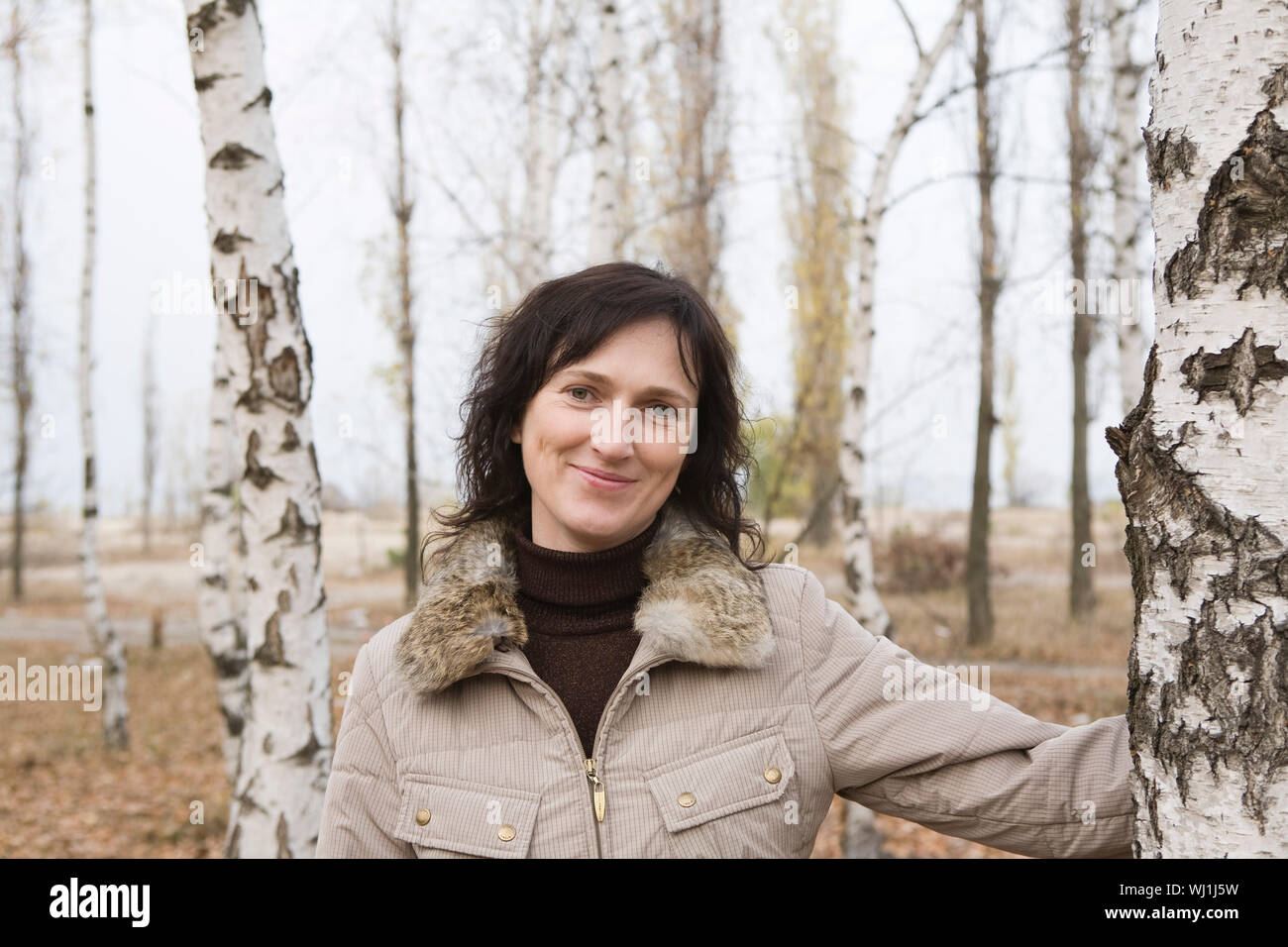 Portrait of a smiling woman standing along trees in field Stock Photo ...