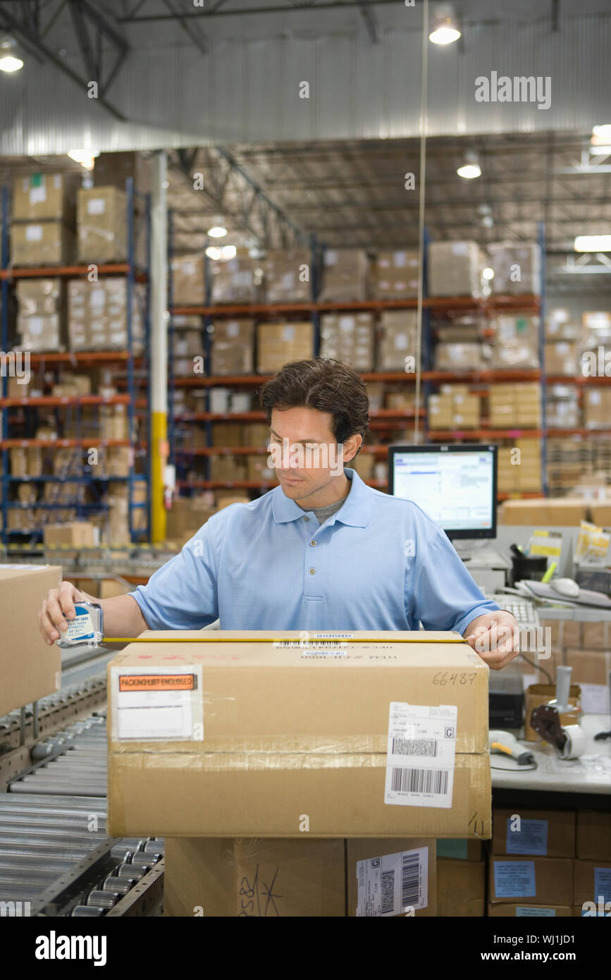 Man measuring box in distribution warehouse Stock Photo - Alamy