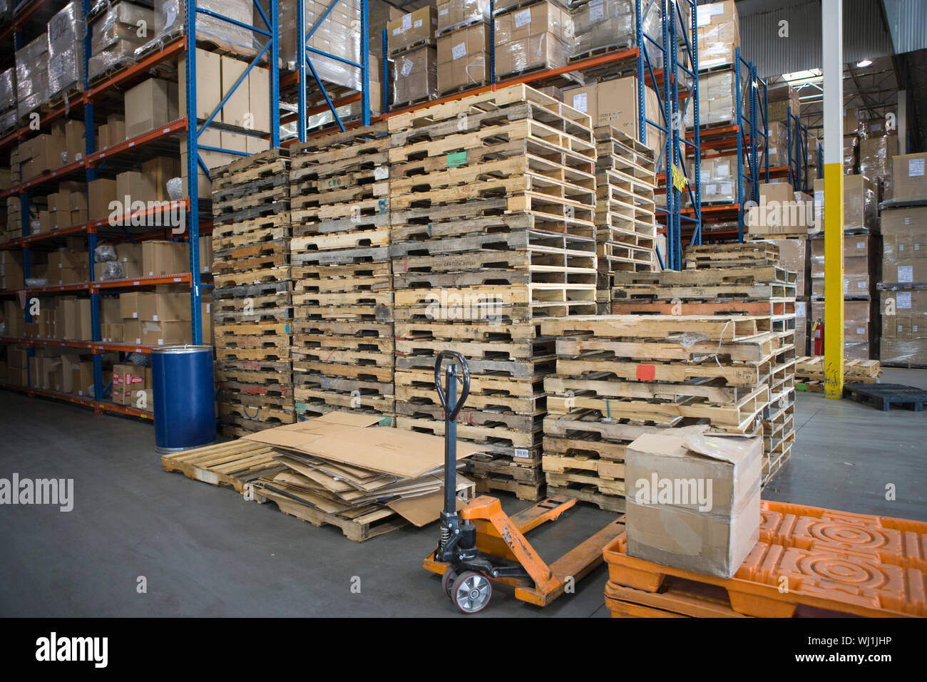 Wooden pallets stacked in distribution warehouse Stock Photo - Alamy