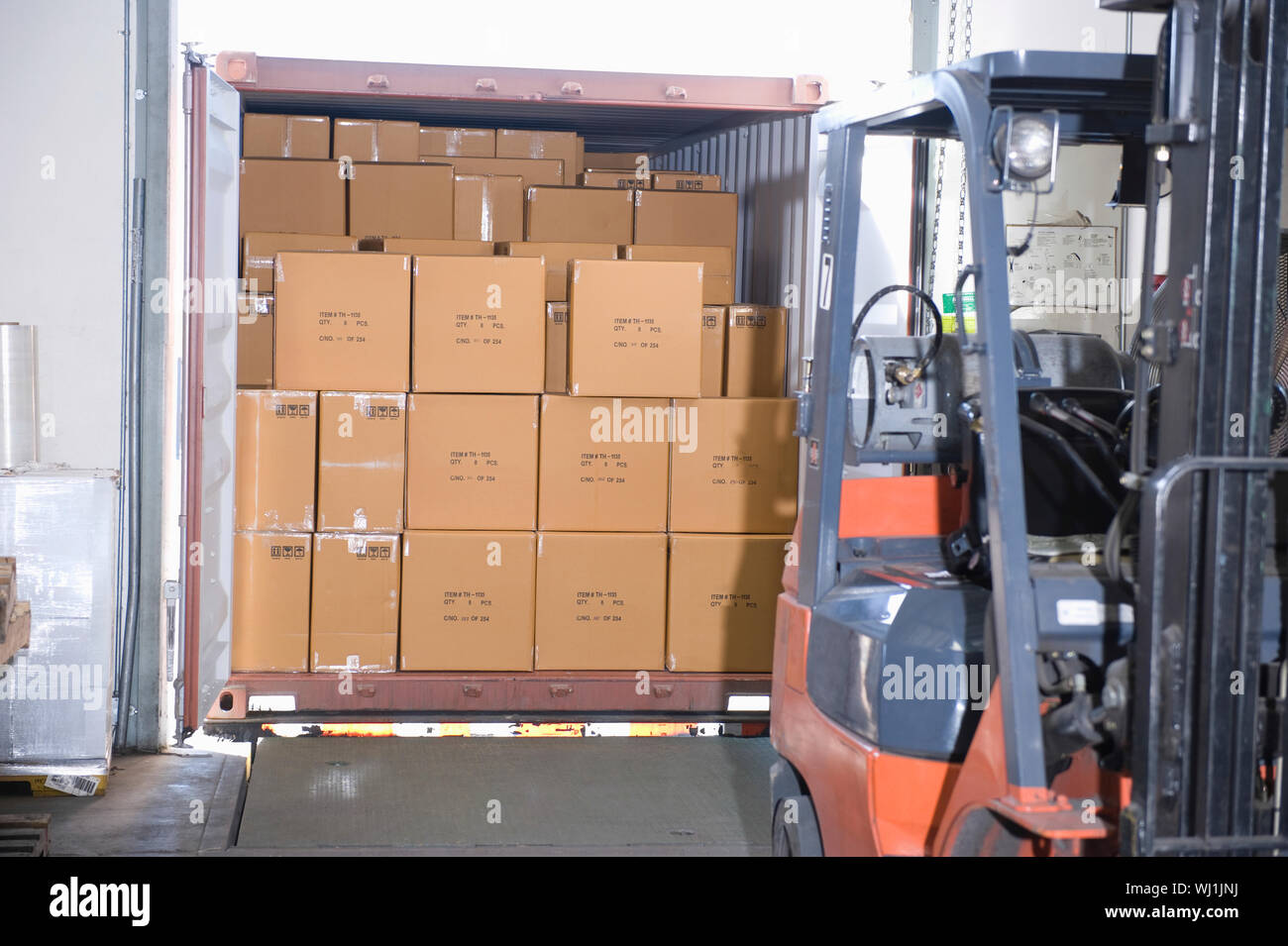 Cardboard boxes and fork lift truck in distribution warehouse Stock ...