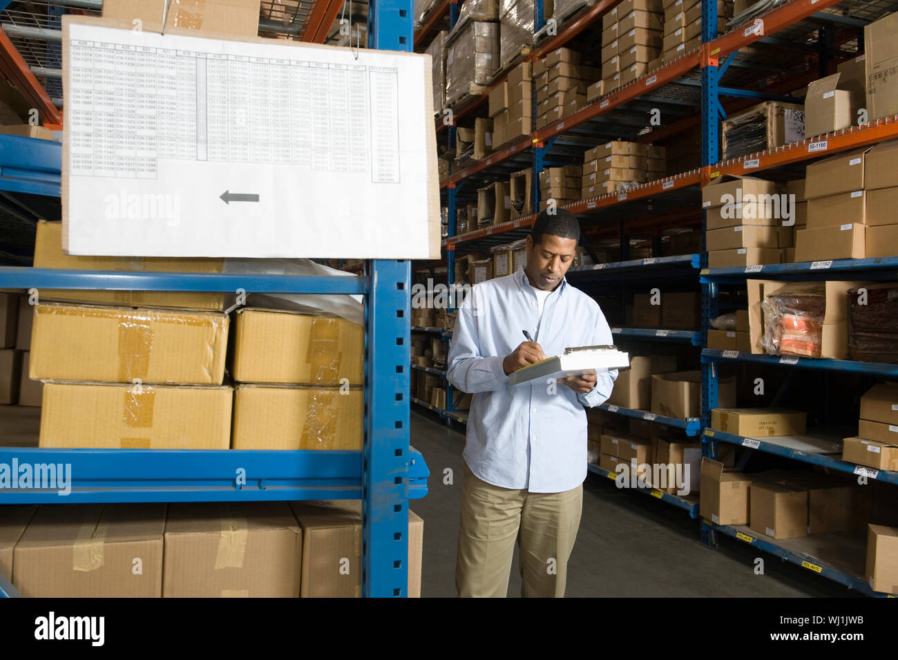 Man inspecting boxes in distribution warehouse Stock Photo - Alamy