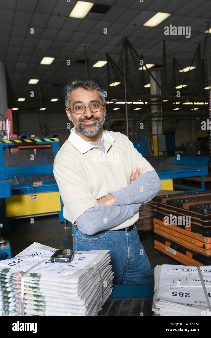 Portrait of a smiling man standing in factory with newspapers Stock ...