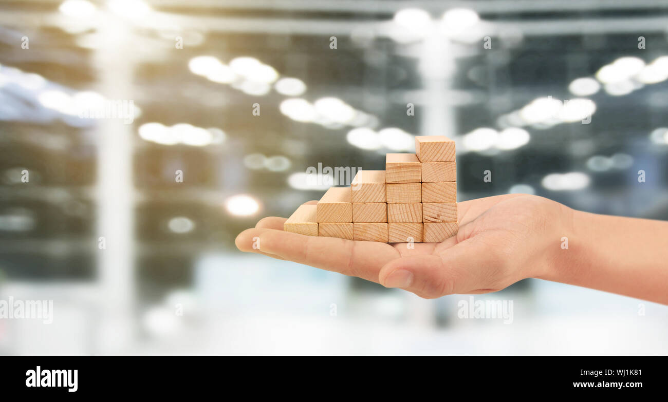 Wood block stacking as step stair with arrow up in a hand. Ladder ...
