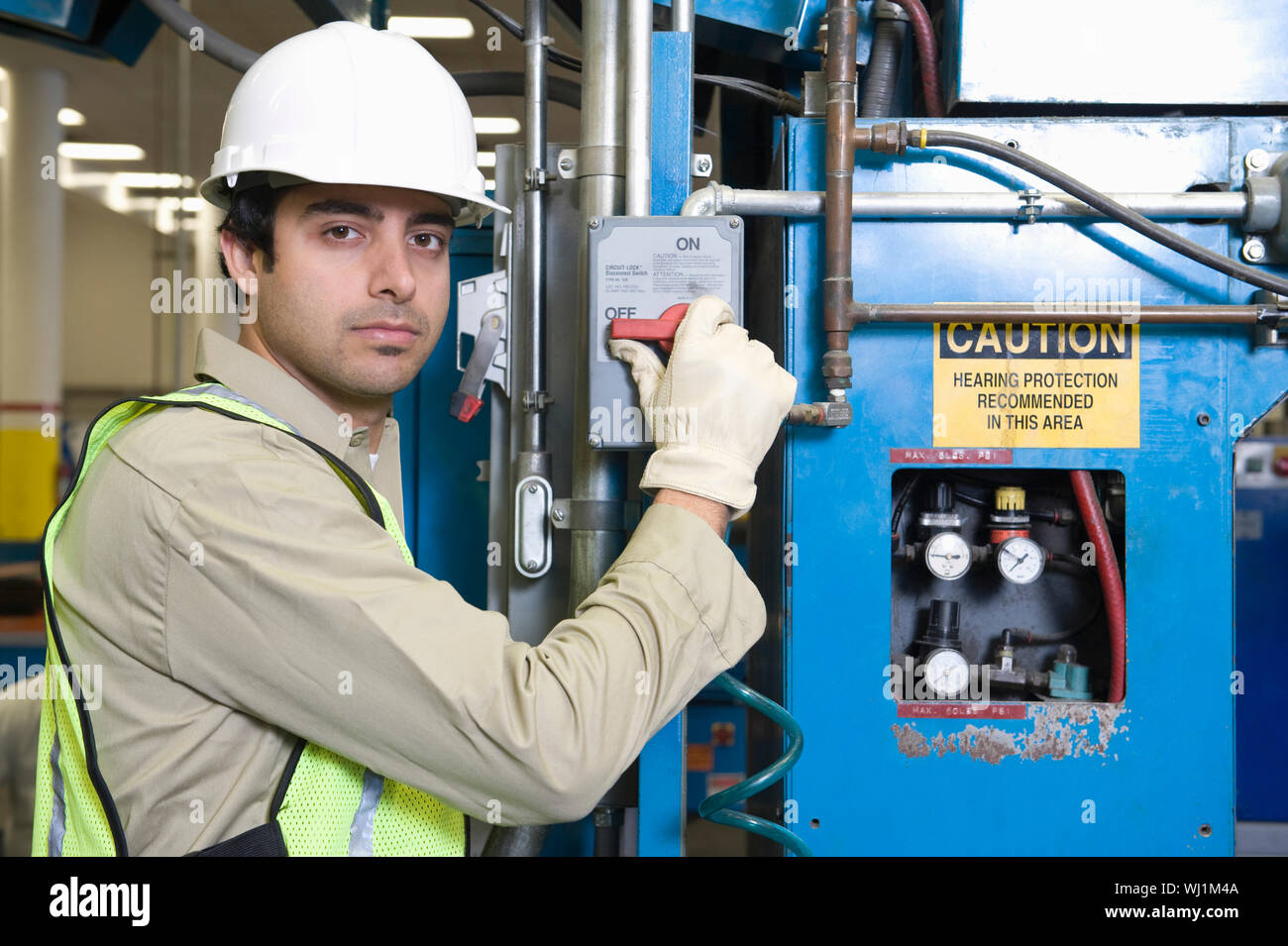 Closeup portrait of a young man pushing button in newspaper factory ...