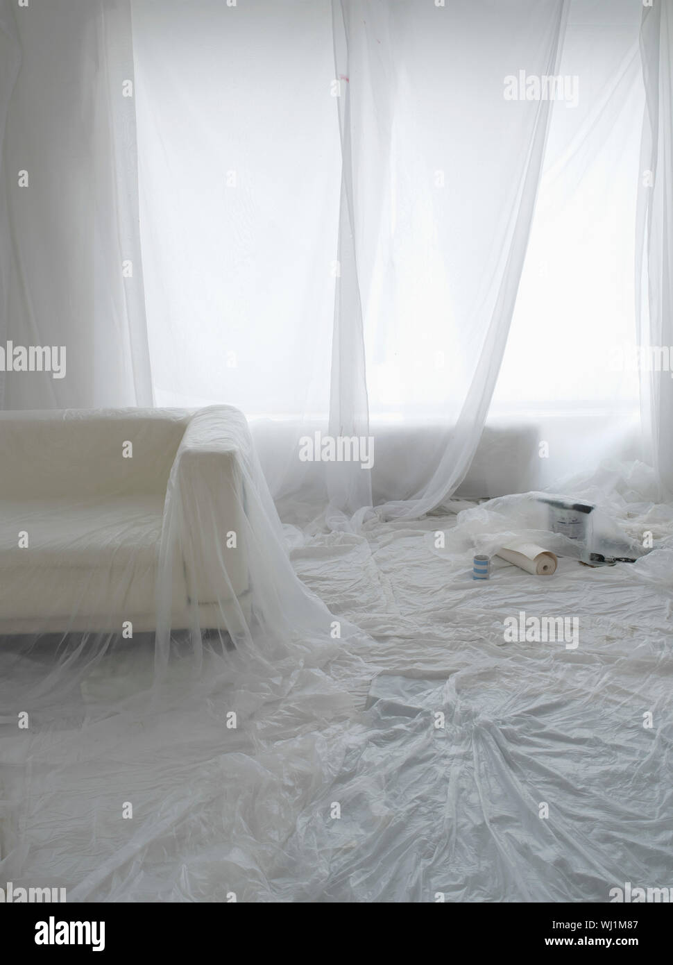 Empty room covered in dust sheets prepared for painting and decorating ...