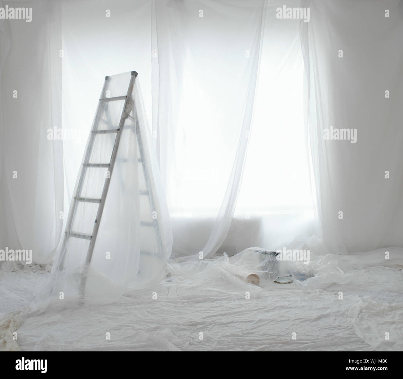 Empty room covered in dust sheets prepared for painting and decorating ...