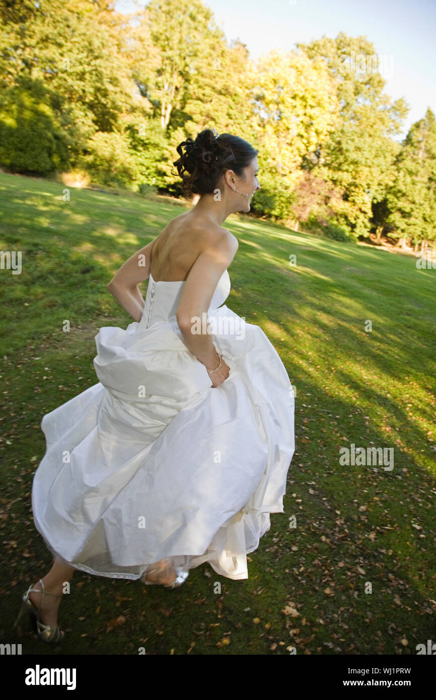 Full length side view of a smiling bride running in park Stock Photo ...