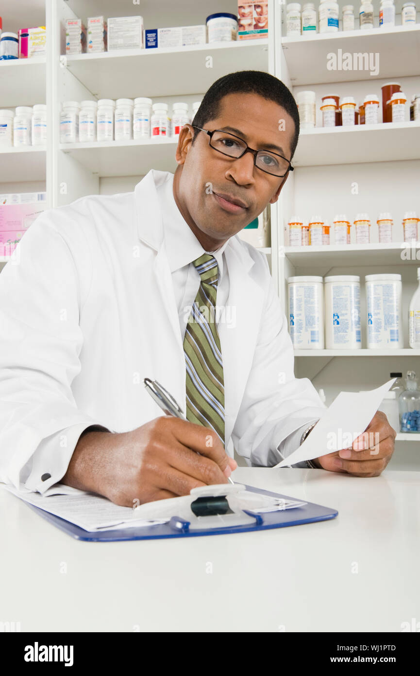 Portrait of a confident pharmacist writing prescription with medicines ...