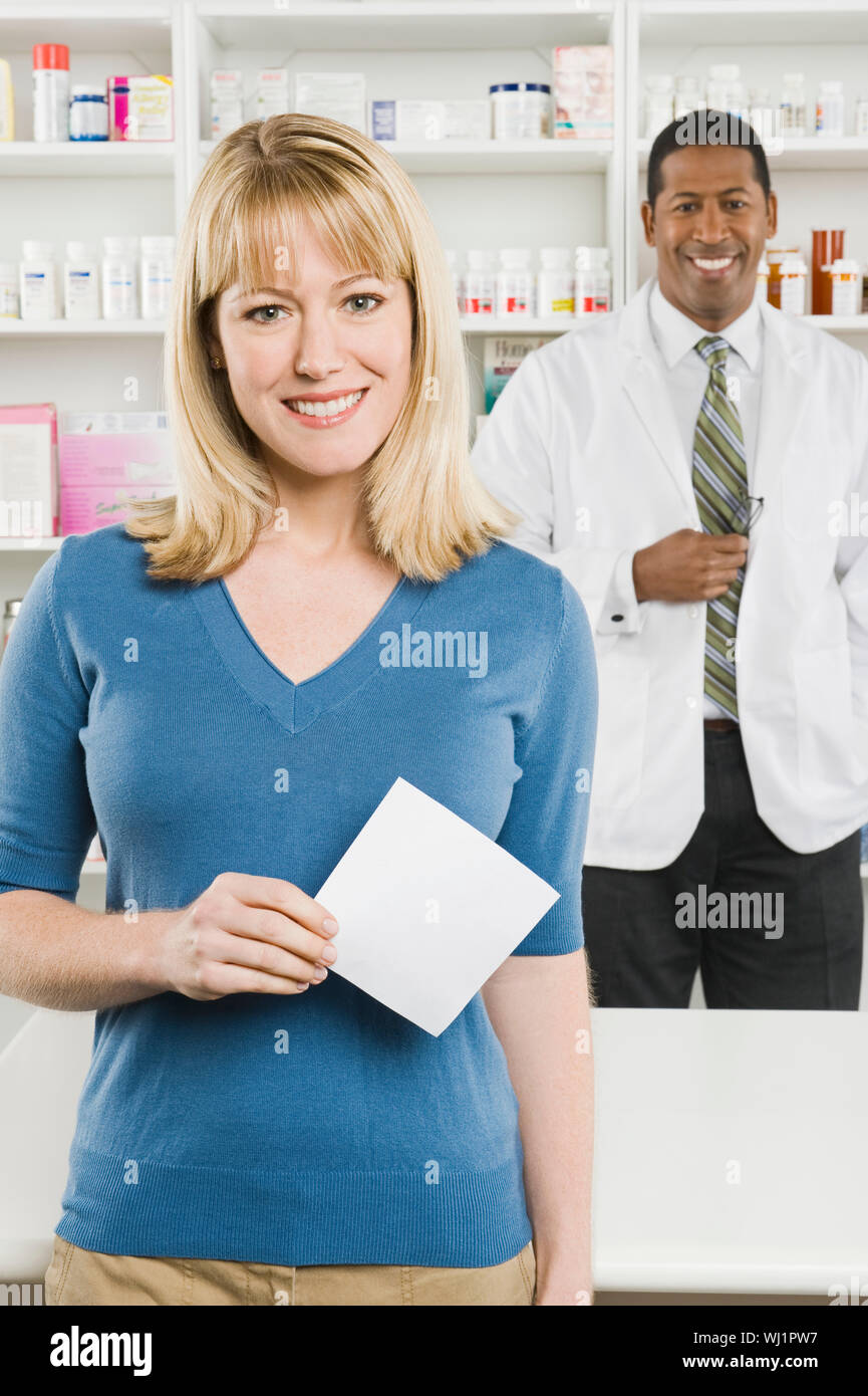 Portrait of a happy female customer holding prescription with ...