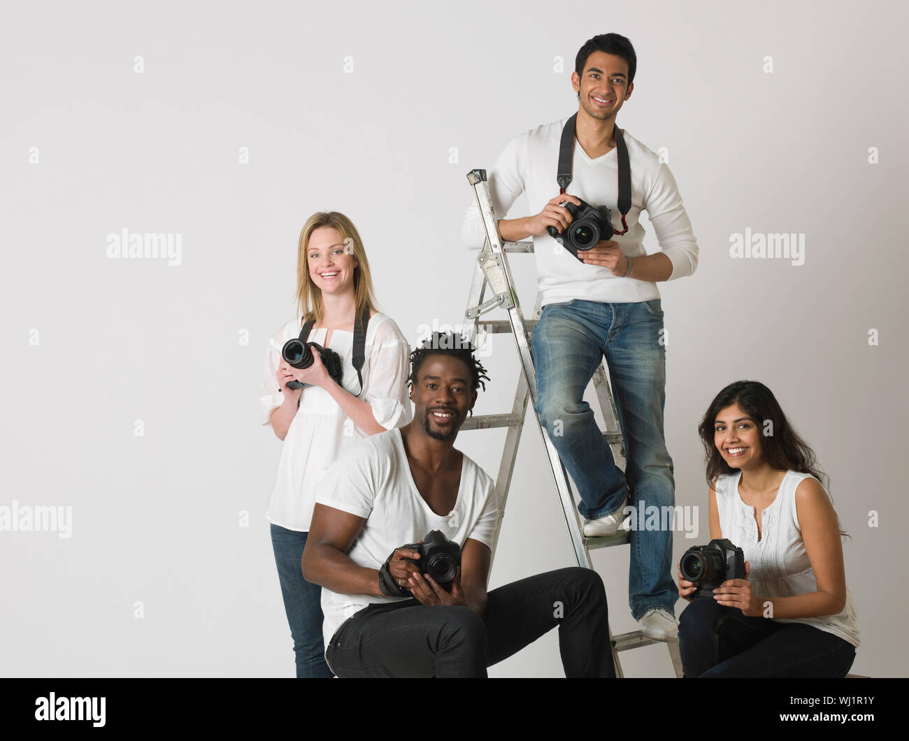 Group portrait of multiethnic young people holding cameras in studio ...
