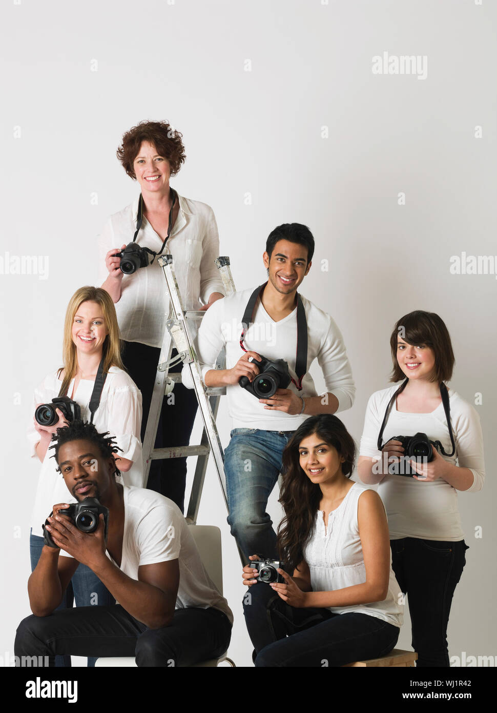 Group portrait of multiethnic young people holding cameras in studio ...