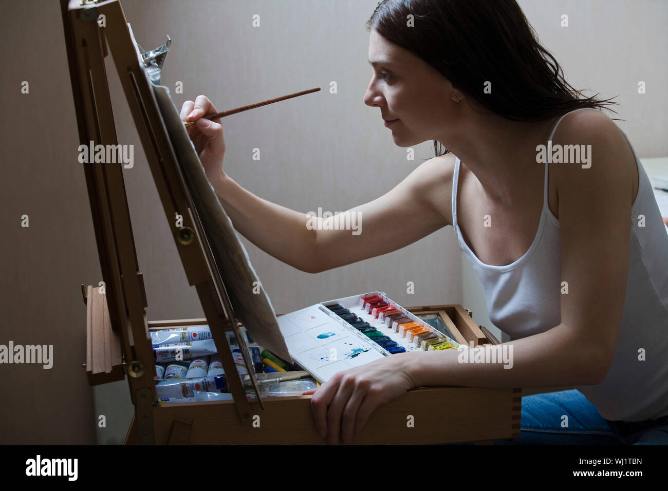 Side view of a young woman painting on easel Stock Photo - Alamy