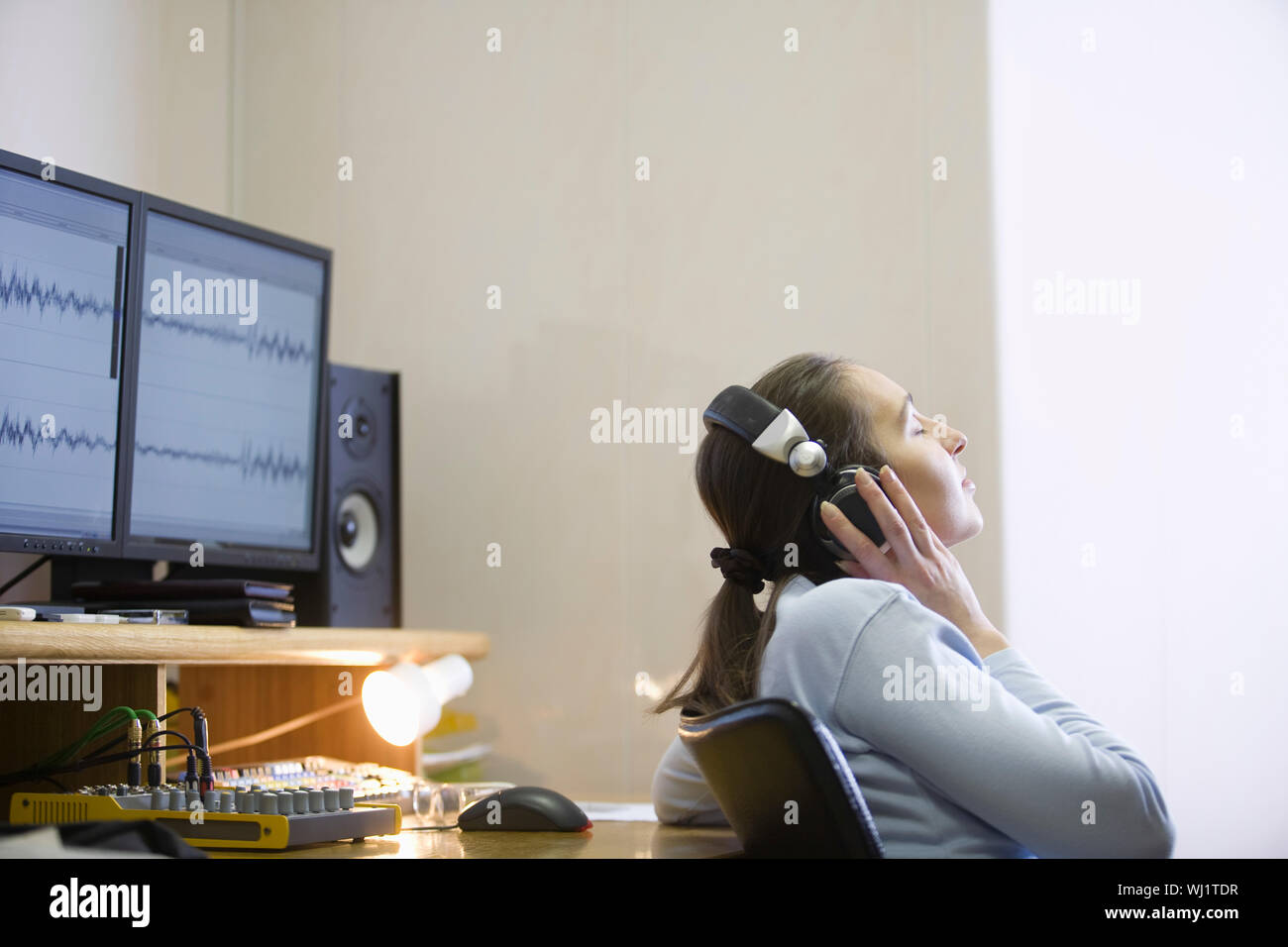 Side view of a female sound engineer listening to music Stock Photo - Alamy