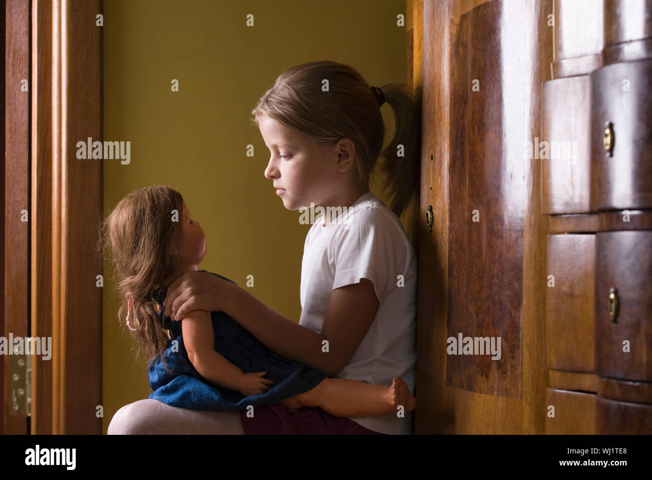 Side view of a little girl playing with her doll in home Stock Photo ...