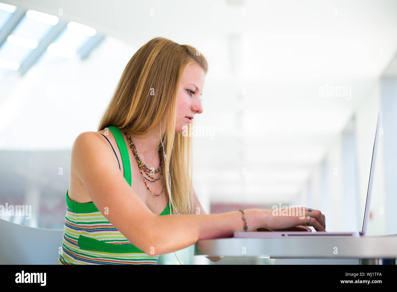 pretty female college student working on her laptop computer on campus ...