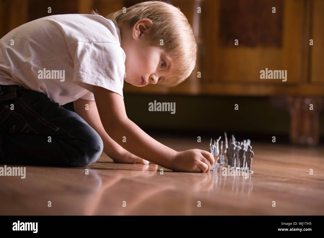Side view of a young boy playing with toy soldiers on floor Stock Photo ...