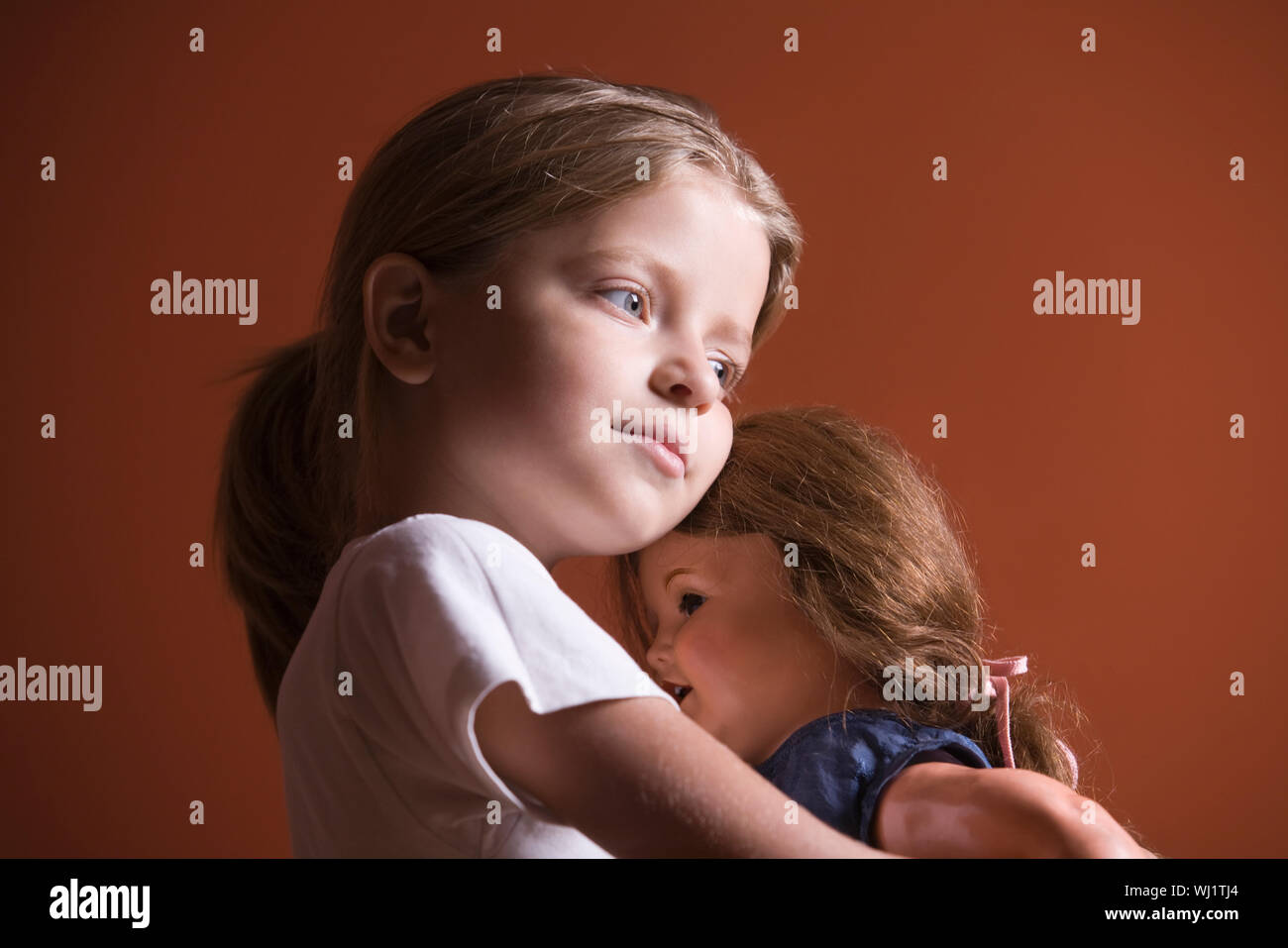 Closeup side view of a little girl embracing her doll Stock Photo - Alamy