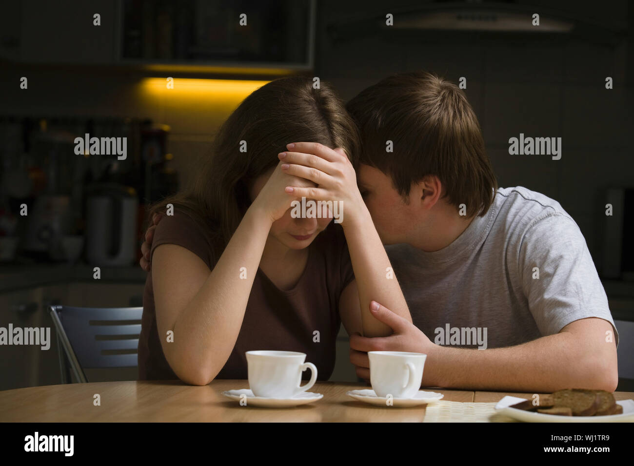 Young man consoling woman at dining table in house Stock Photo - Alamy