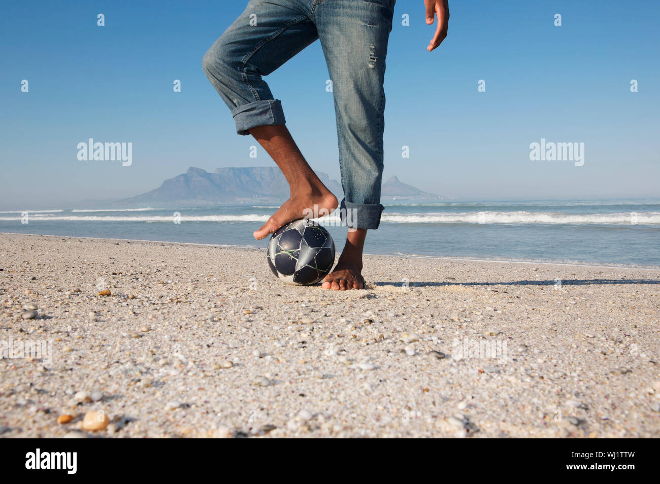 Lowsection of a man with foot on soccer ball at beach Stock Photo - Alamy