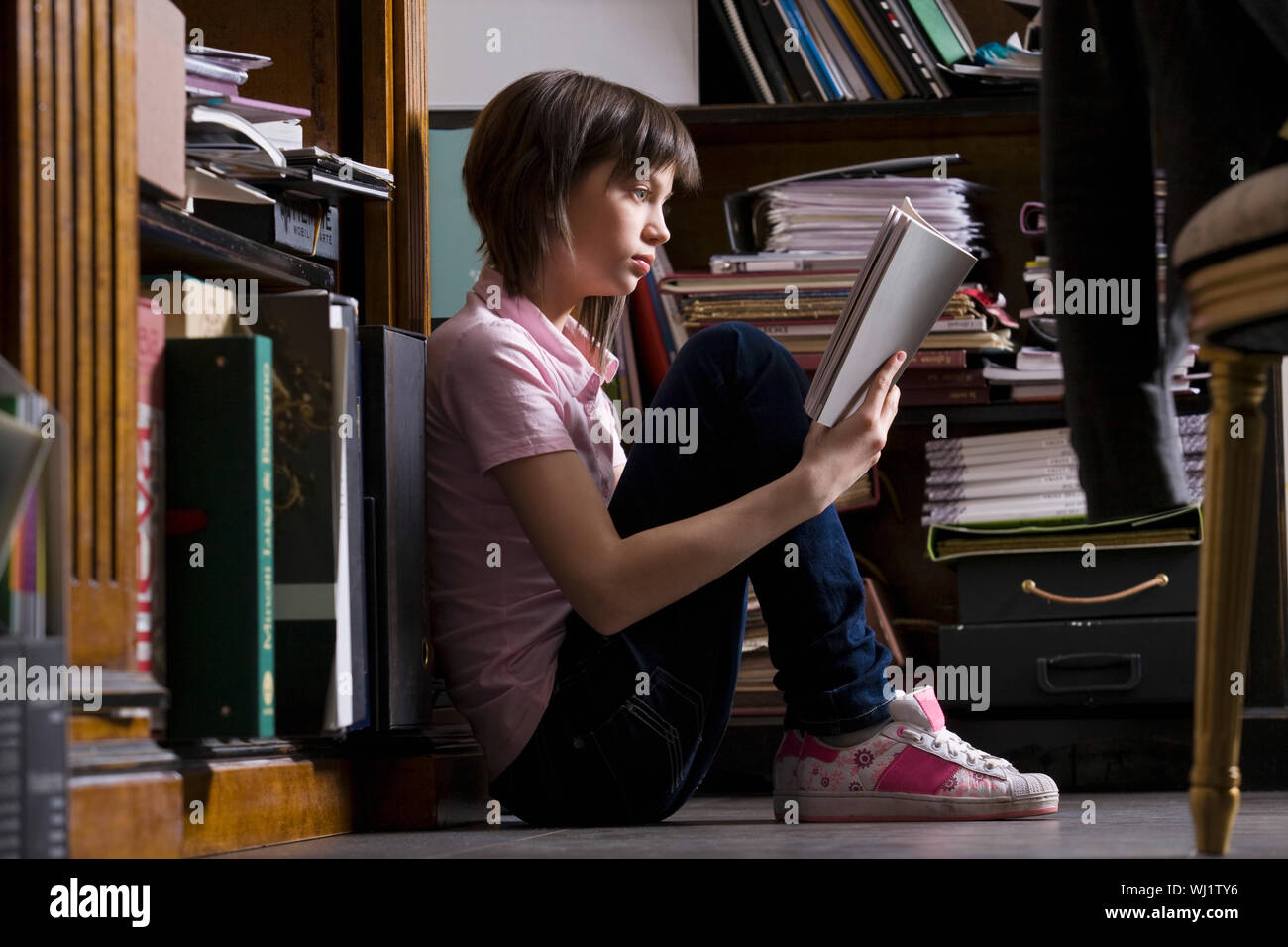 Side view of a young girl reading a book at the library Stock Photo - Alamy