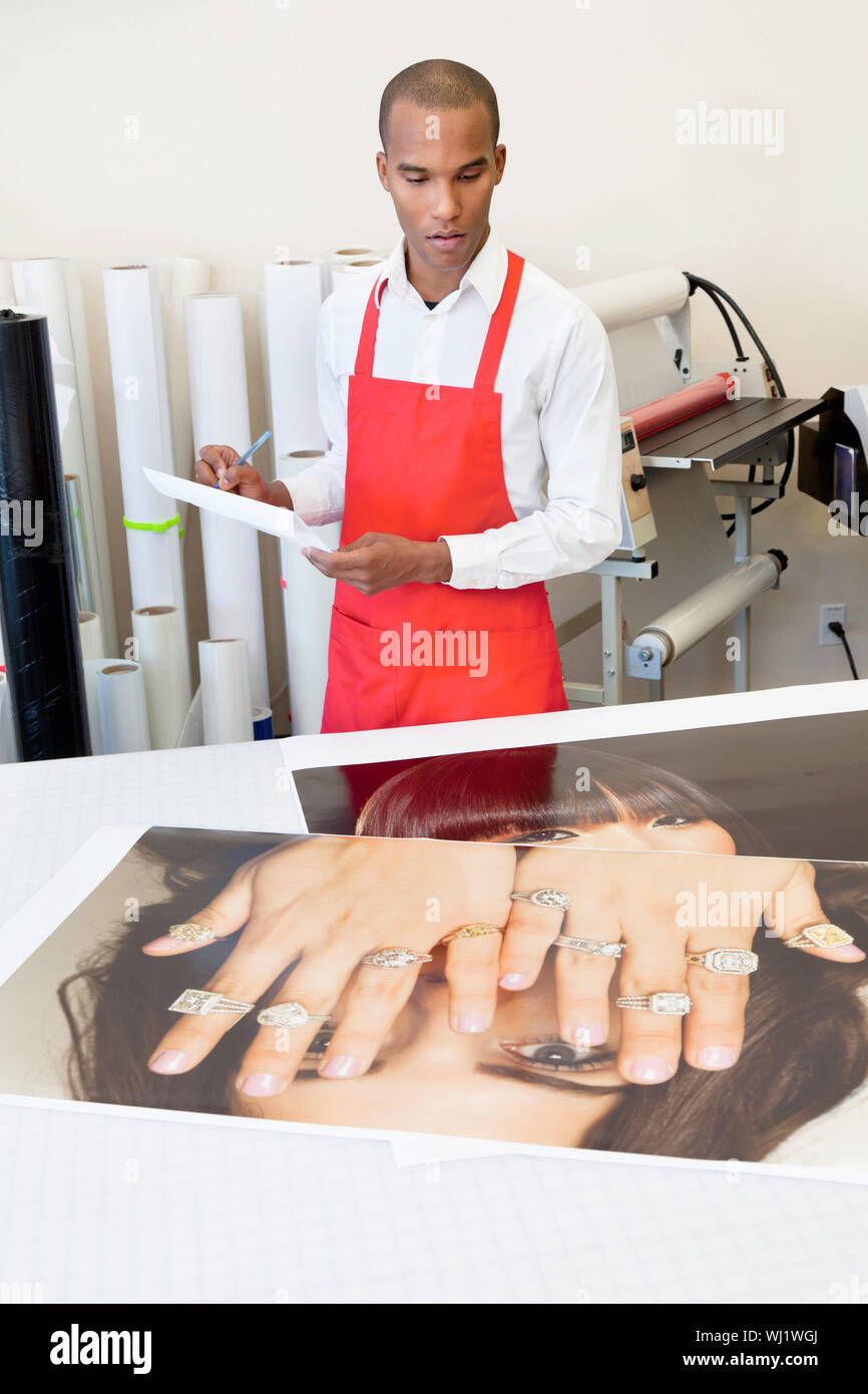Man working at printing press with photo printouts on table Stock Photo ...